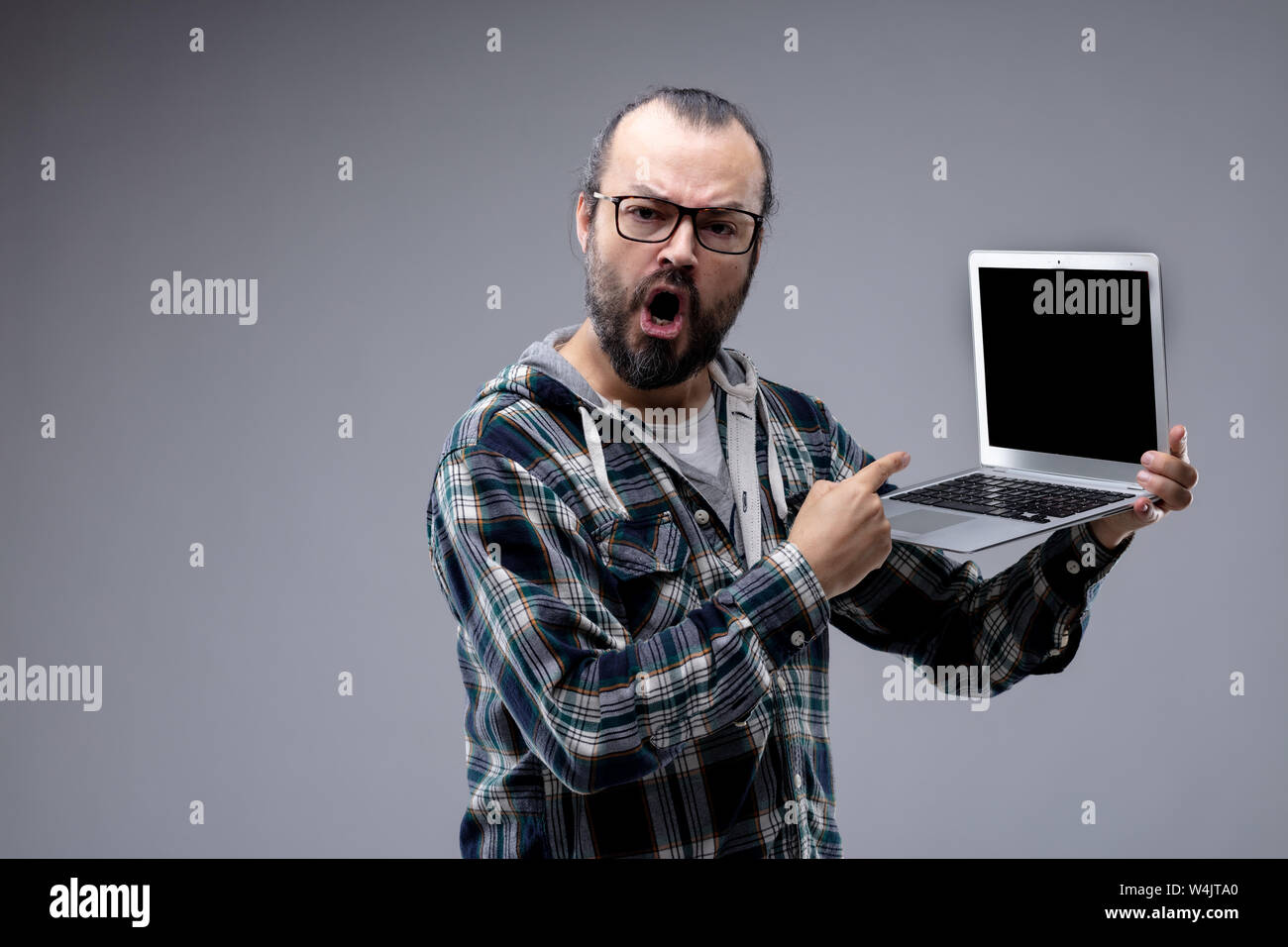 Argumentative irate man pointing at his laptop as he talks to the ...