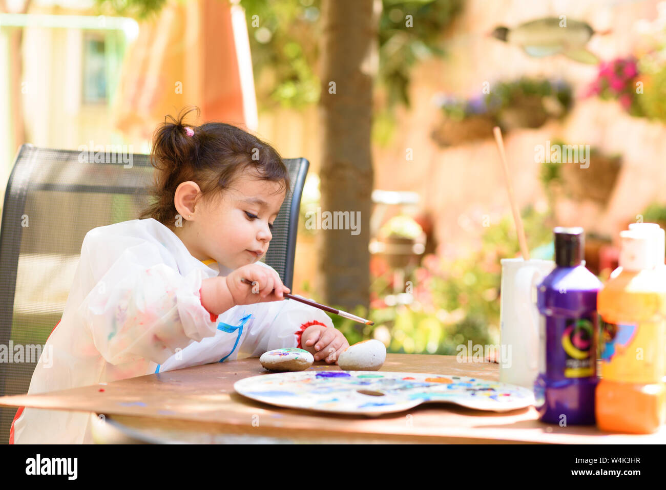 Cute little girl having fun, coloring with brush, writing and painting ...