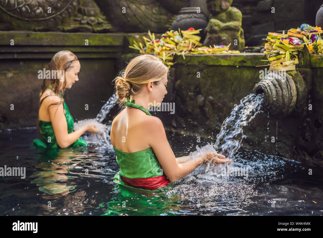 Two women in holy spring water temple in bali. The temple compound ...
