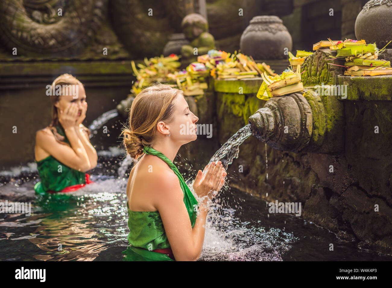 Two women in holy spring water temple in bali. The temple compound ...