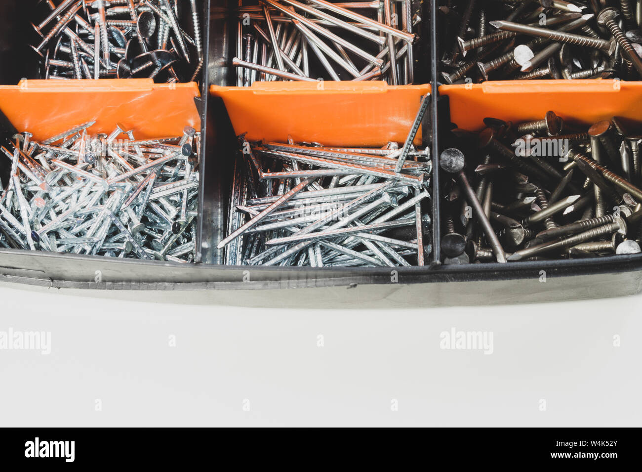 Various metal nails in toolbox background. nails in the cells of the ...