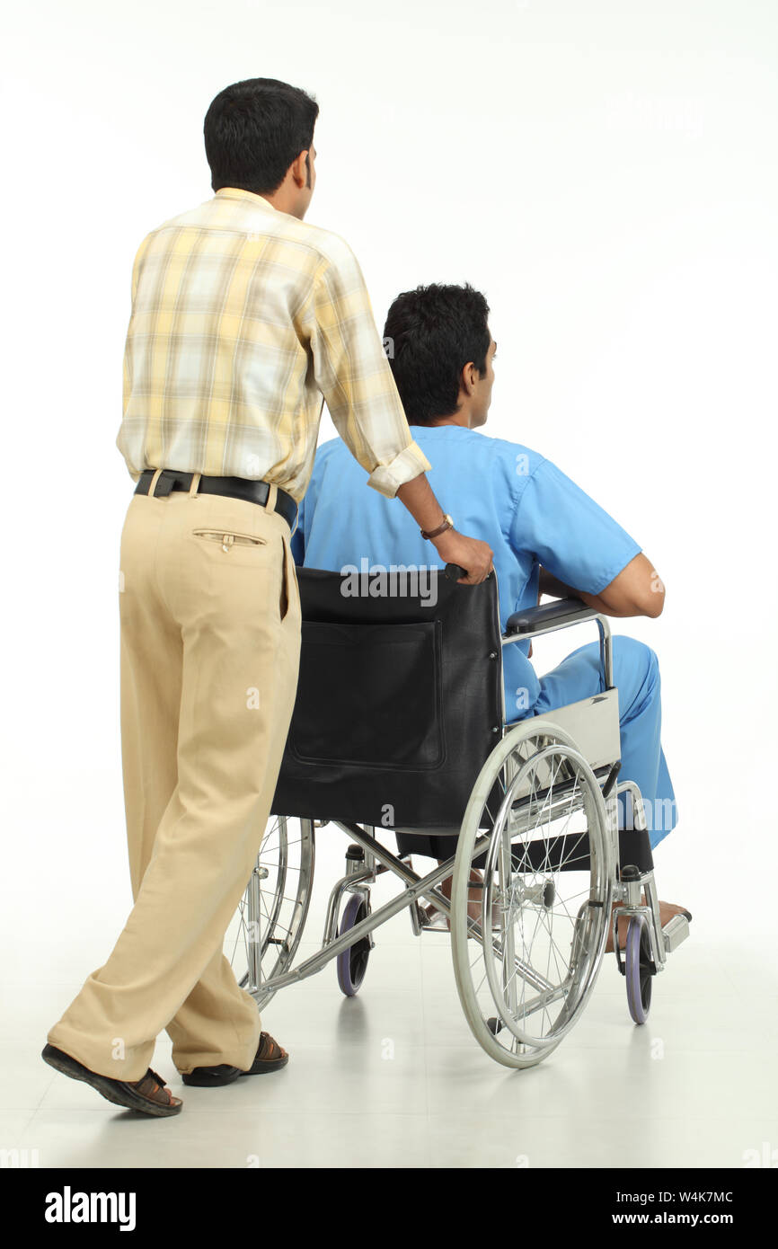 Ward boy pushing a patient on a wheelchair Stock Photo - Alamy