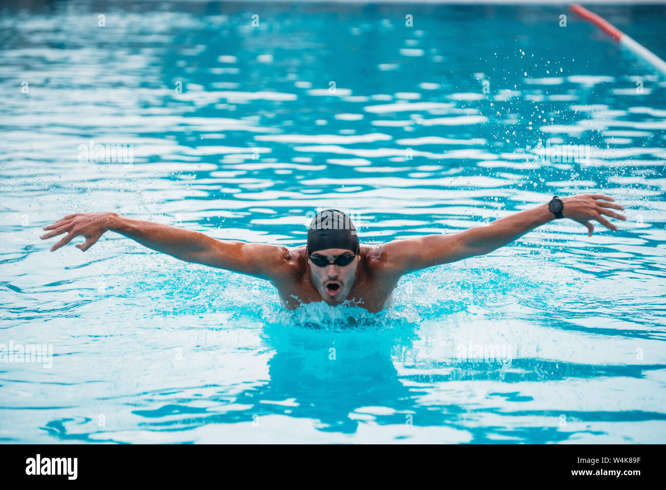 Professional man swimming in butterfly style with hat and goggles at ...