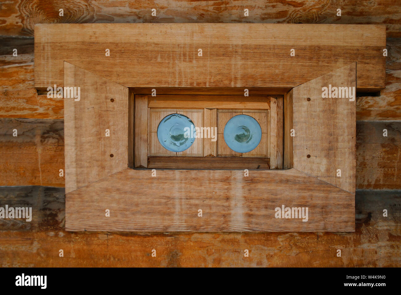 An old wooden window with small round colored glasses in a wooden house ...