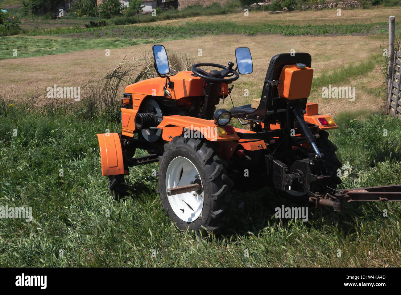 The orange minitractor works in the field. Agricultural multifunction ...
