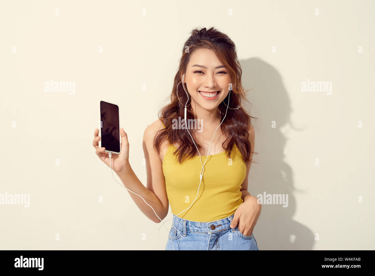 Portrait of a cheerful beautiful girl holding mobile phone isolated ...