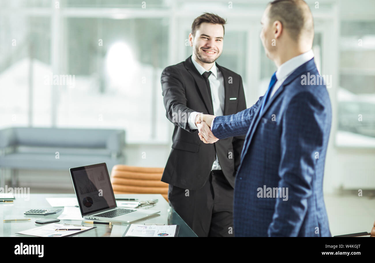 handshake of business partners on the background of the workplace.the ...