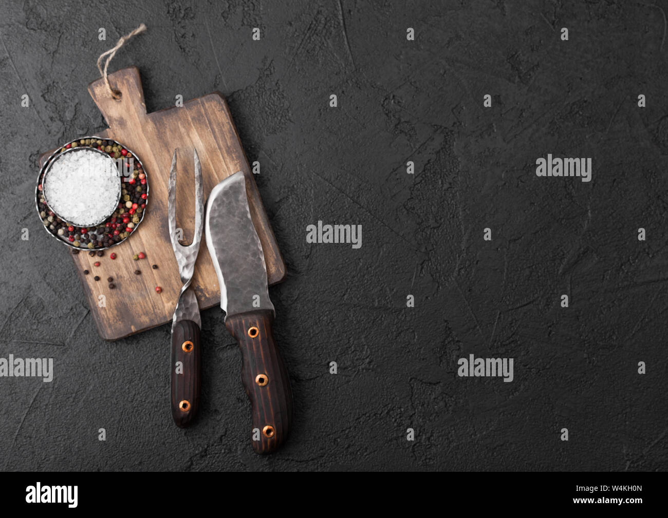 Vintage meat knife and fork on vintage chopping board and black stone ...