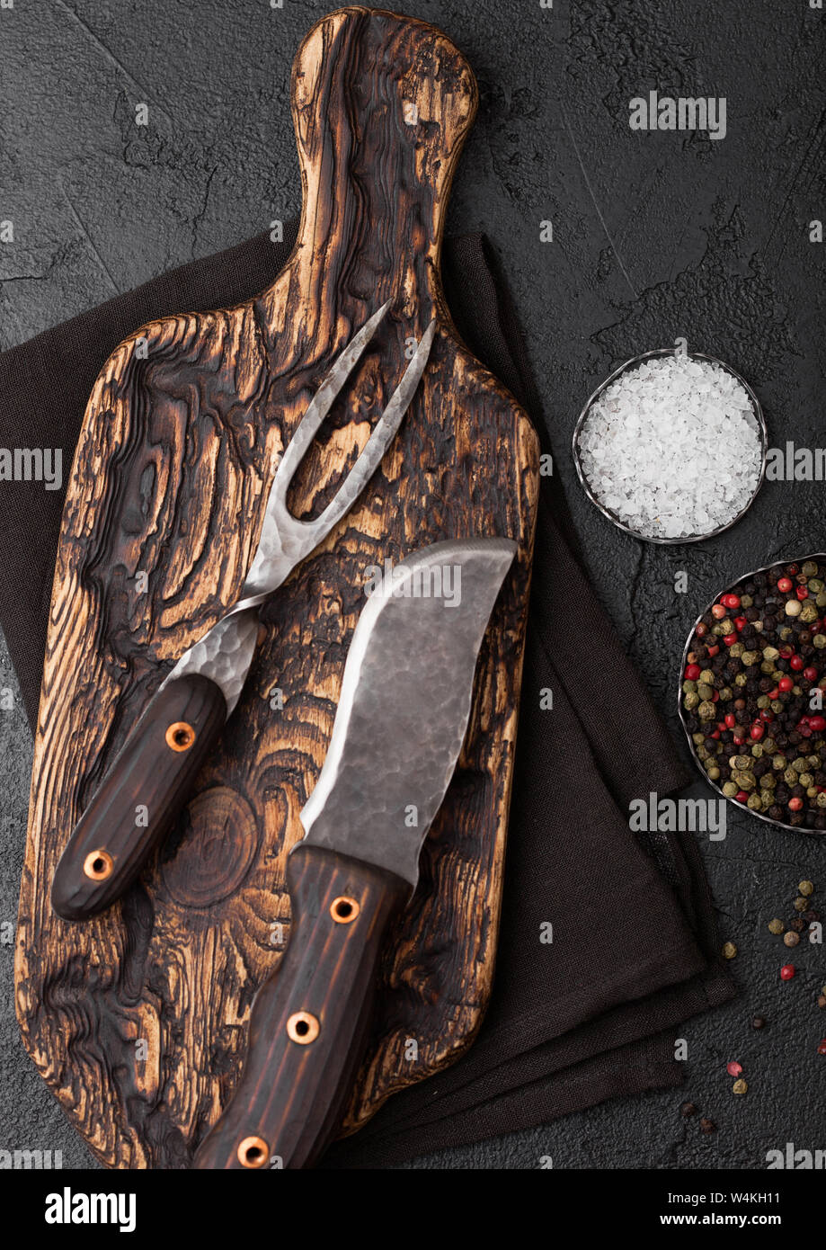 Vintage meat knife and fork on vintage chopping board and black stone ...