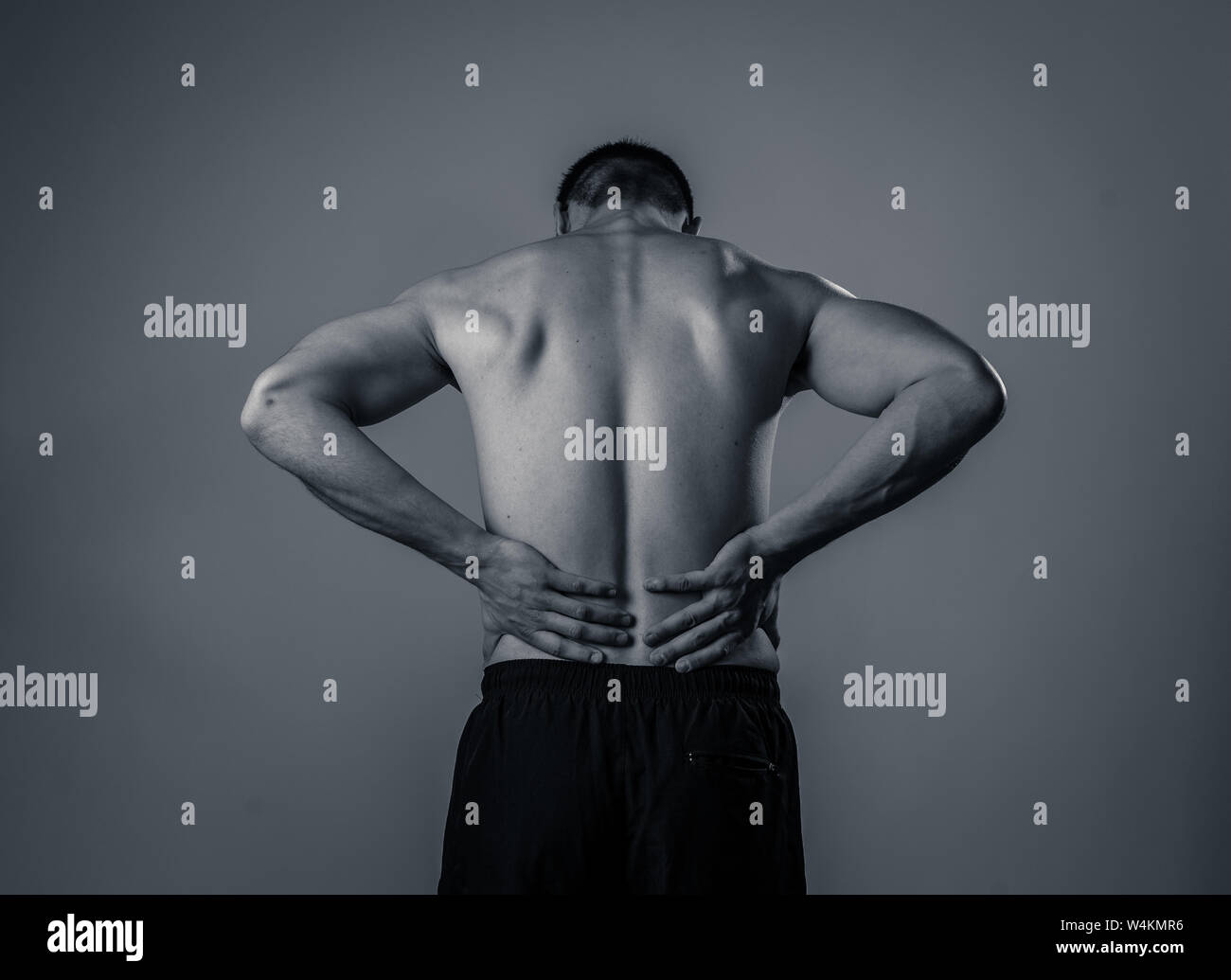 Young muscular fitness man touching and grabbing his lower back ...