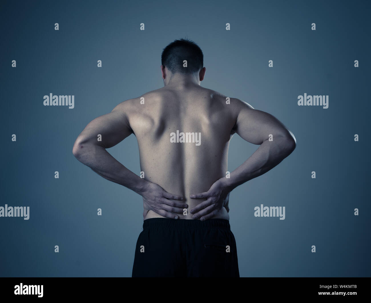 Young muscular fitness man touching and grabbing his lower back ...