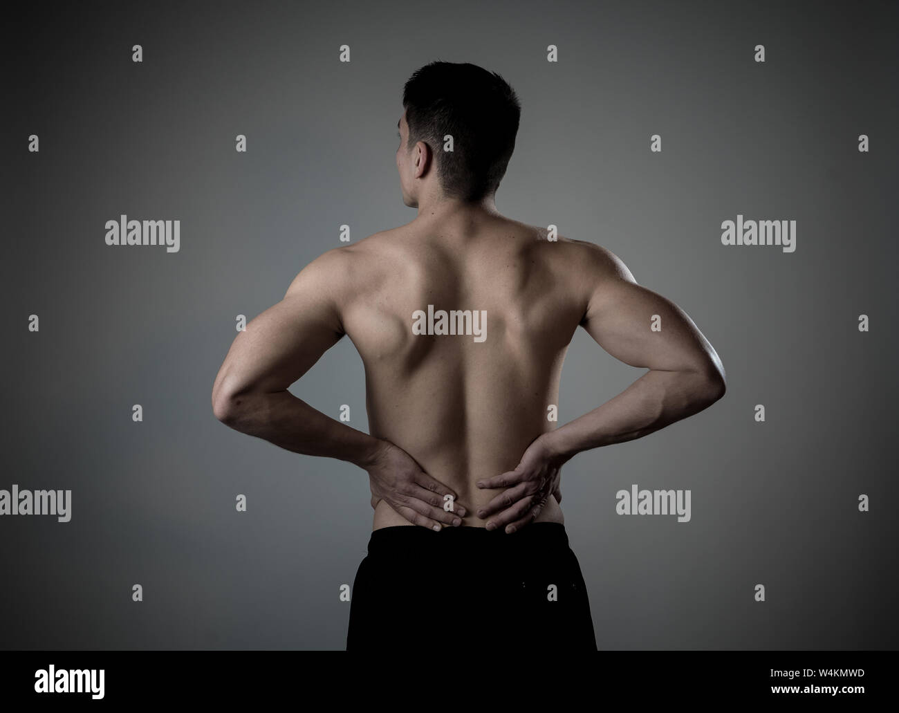 Young muscular fitness man touching and grabbing his lower back ...