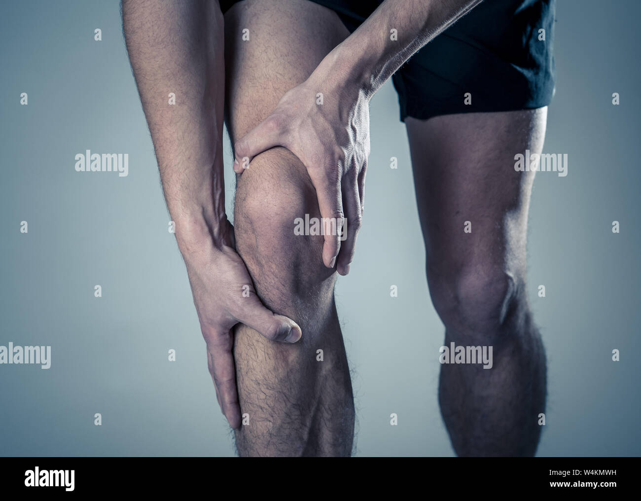 Young fit man holding knee with hands in pain after suffering muscle ...