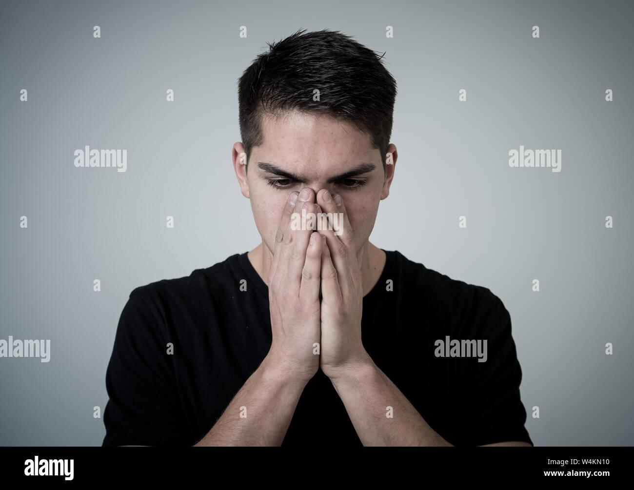 Close up of a young sad mixed race man, serious and concerned, looking ...
