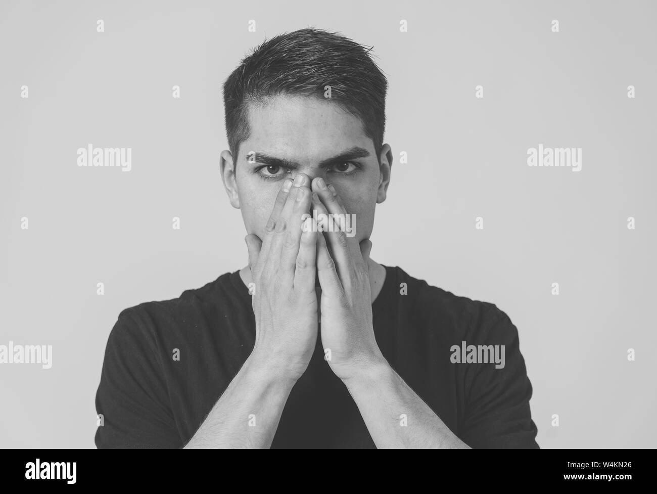 Close up of a young sad mixed race man, serious and concerned, looking ...