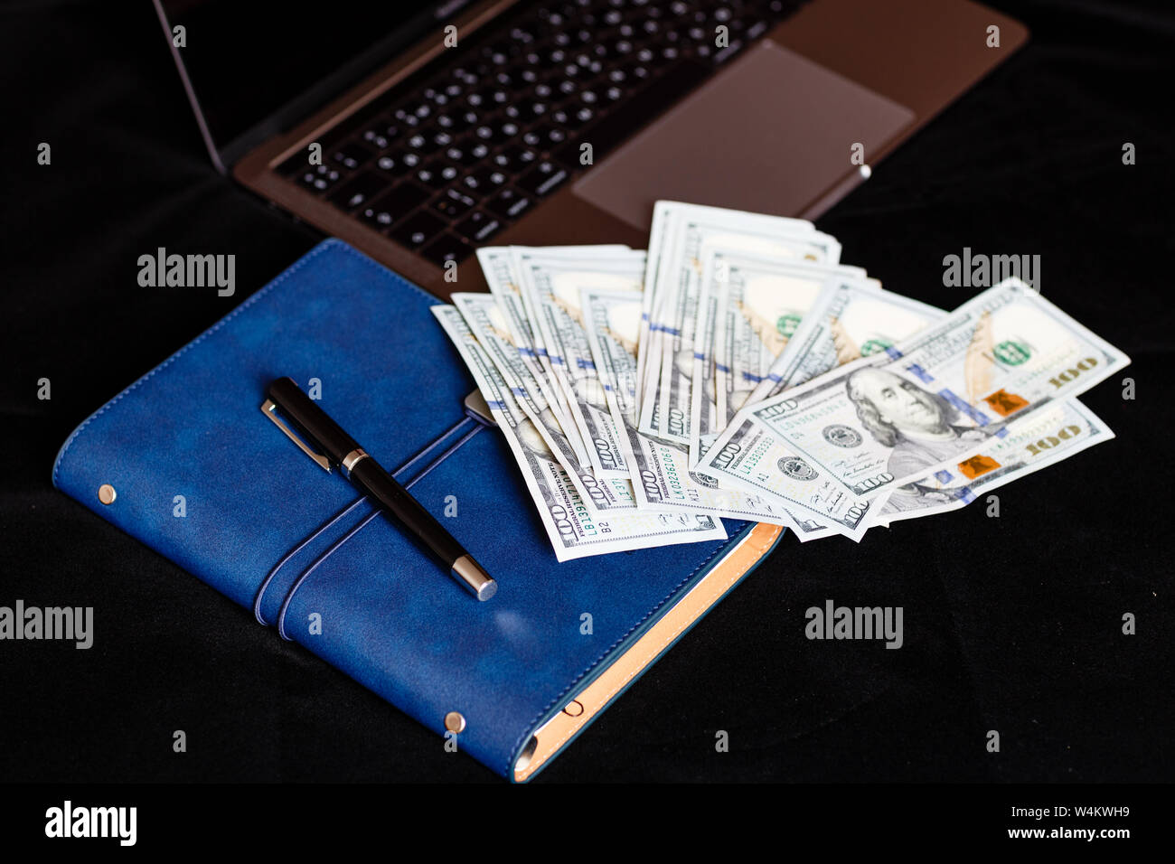 Desktop flatlay: laptop, notebook, pen and cash money lying on black ...