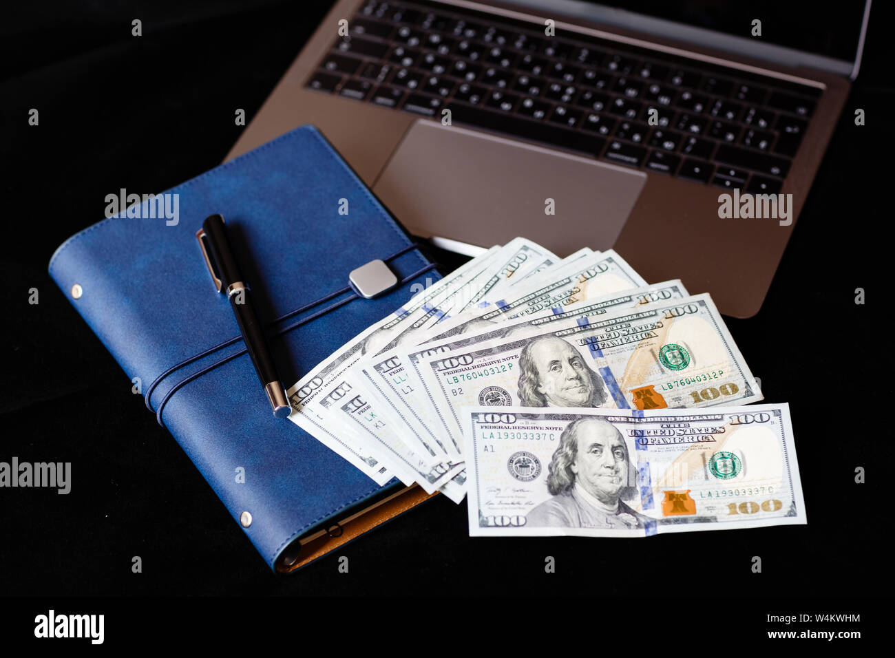 Desktop flatlay: laptop, notebook, pen and cash money lying on black ...