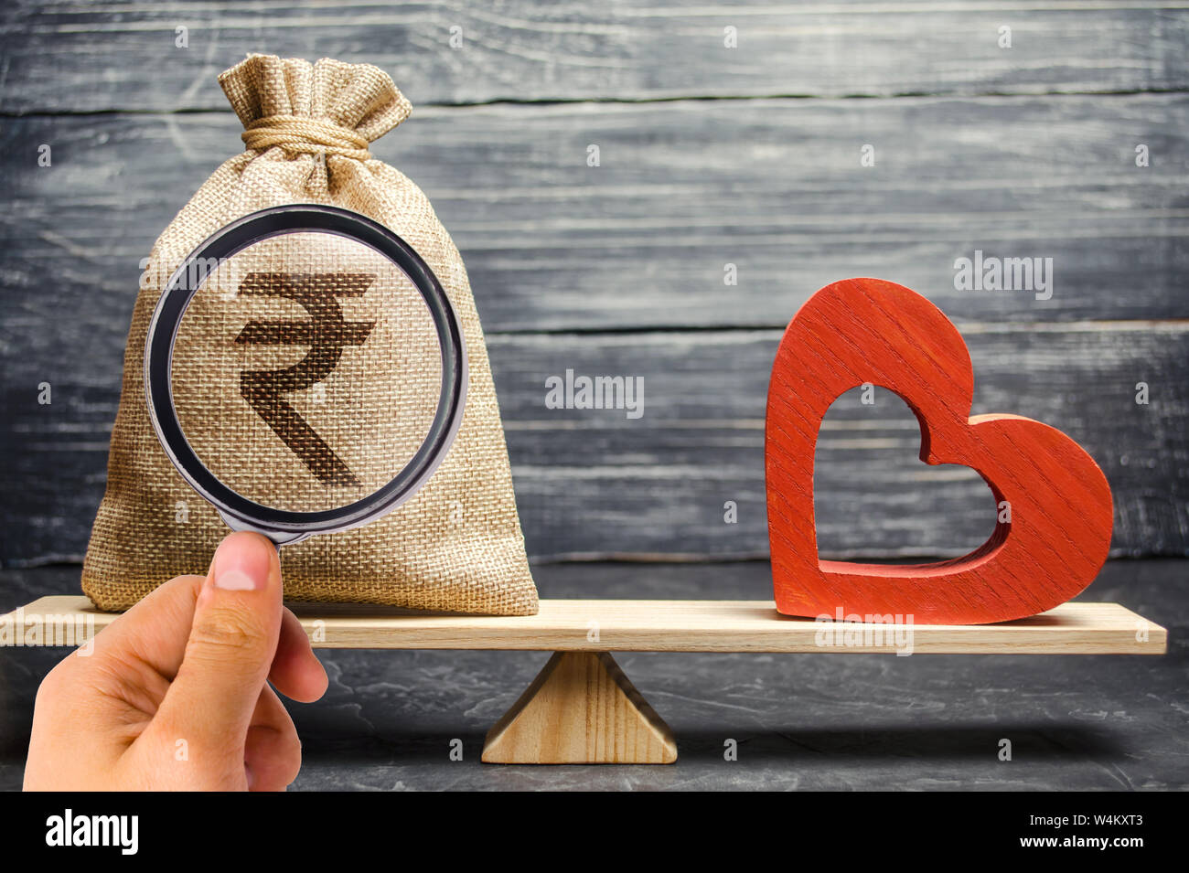 Money bag with indian rupee (rupiah) and red wooden heart on the scales ...