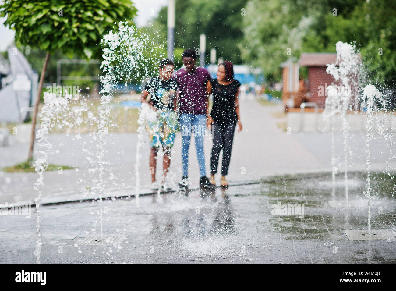 Three african american friends walking on fountains. Having fun ...