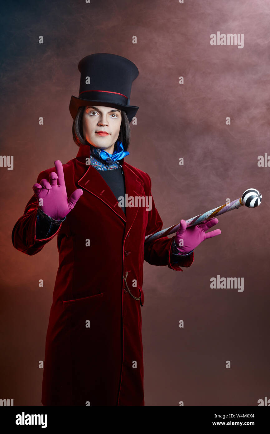 Fabulous circus man in a hat and a red suit posing in the smoke on a ...