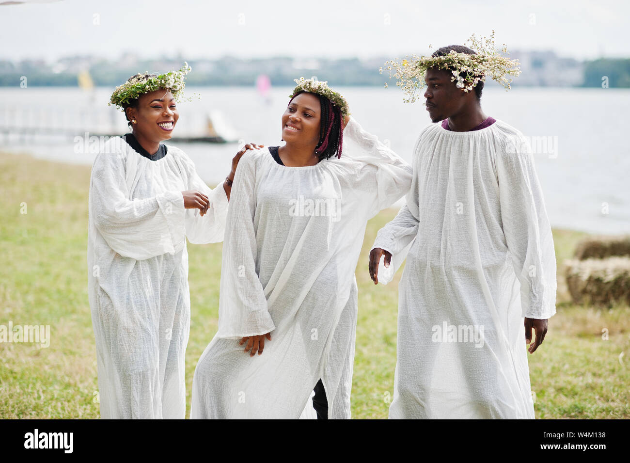 Three african american friends on white cloaks and wreath having fun ...
