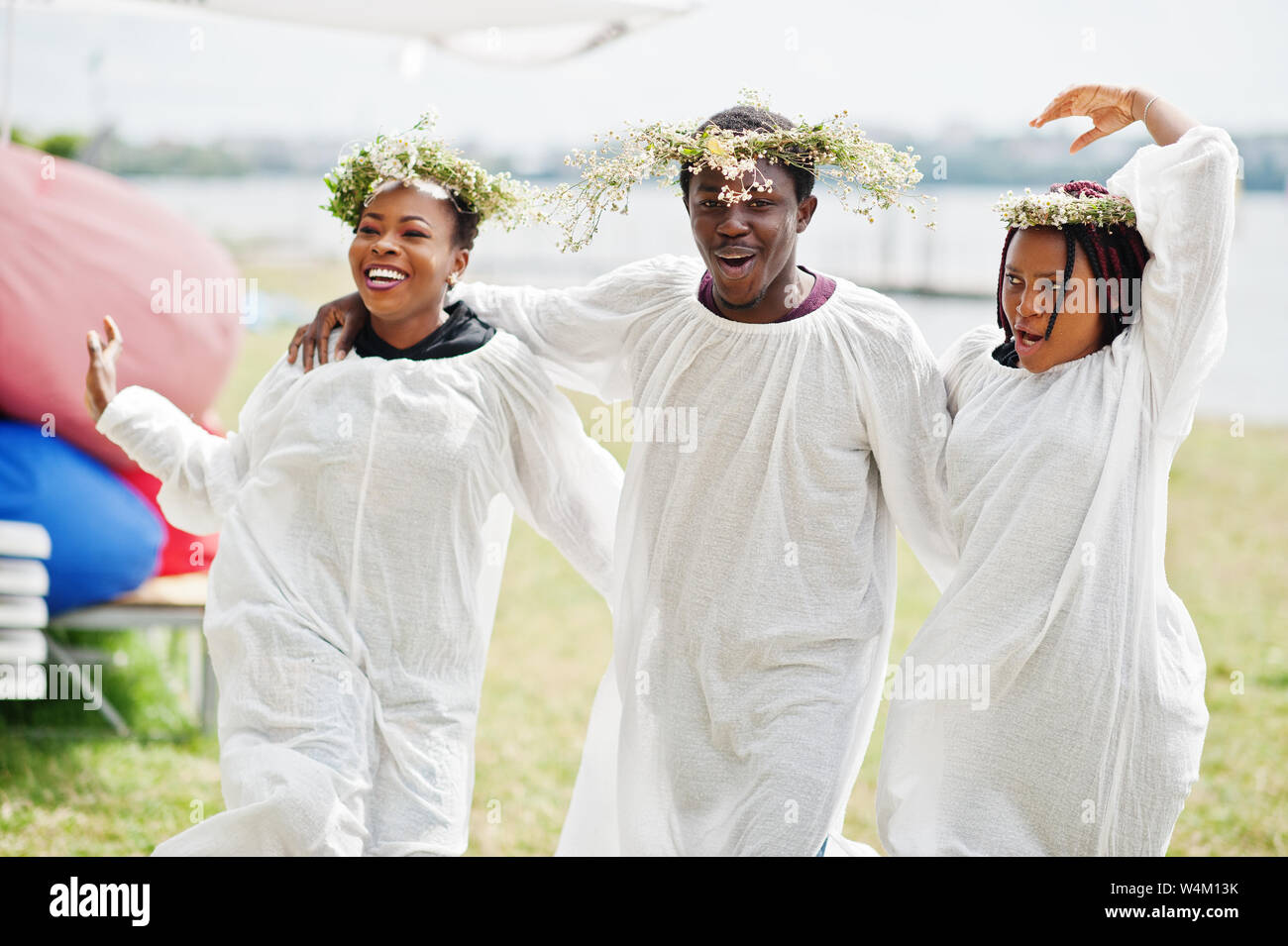 Three african american friends on white cloaks and wreath having fun ...