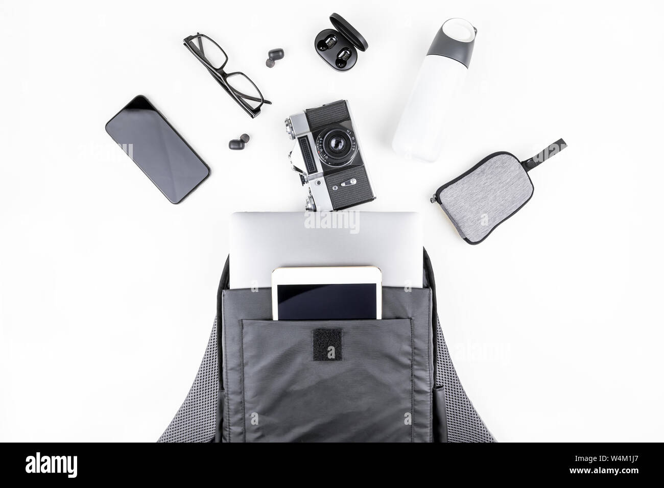 Creative top view flat lay of open backpack with laptop and tablet ...