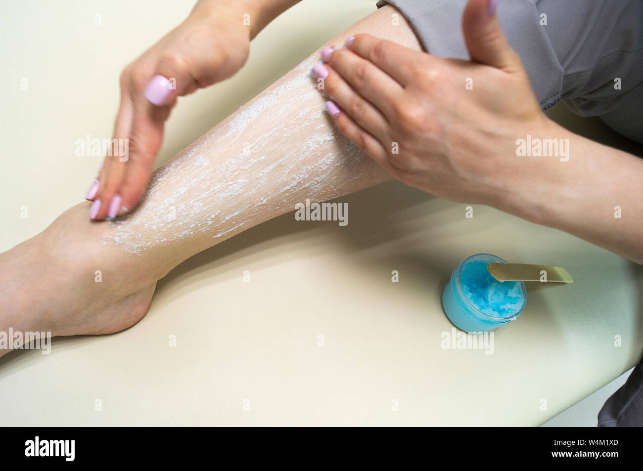 Rejuvenation procedure. The girl puts a blue scrub on her leg Stock ...