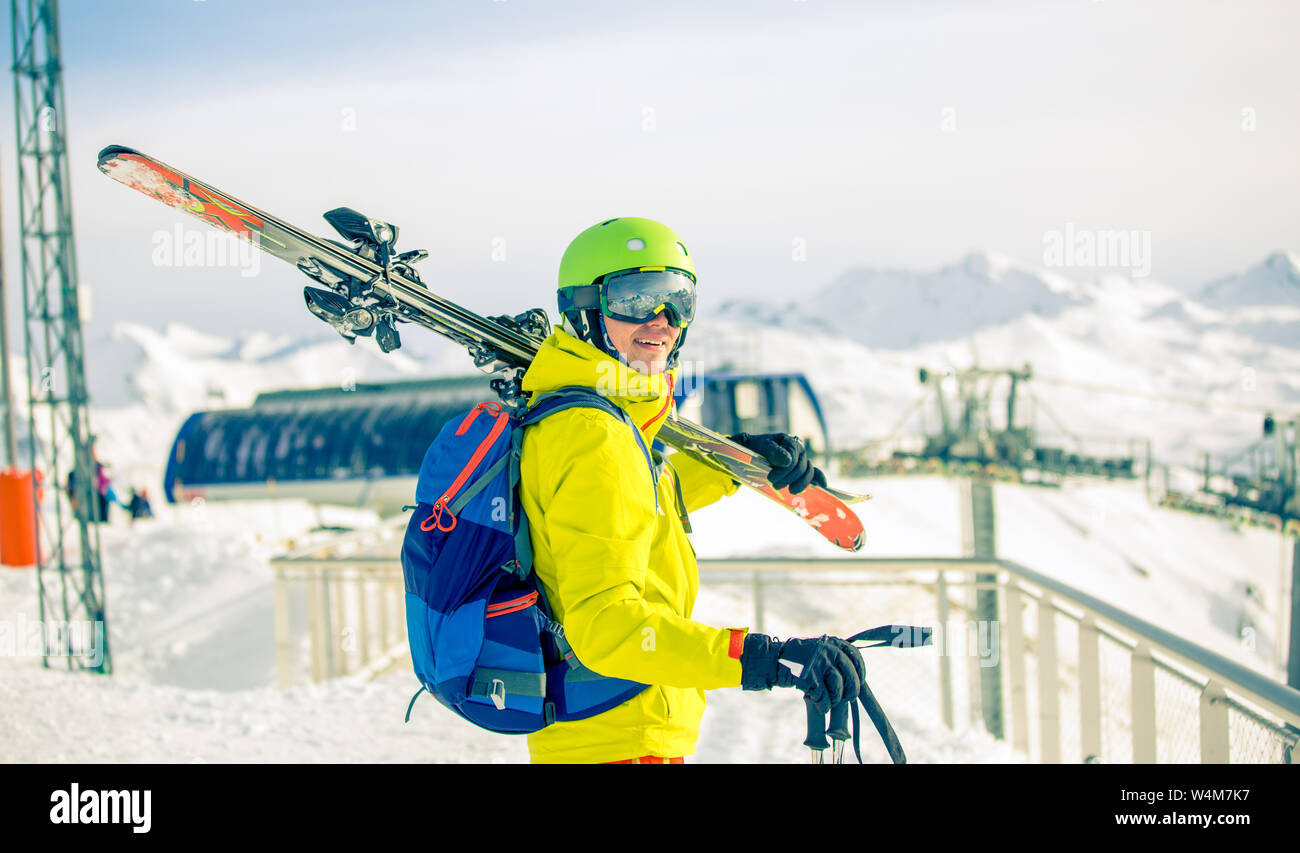 Image of sporty man in helmet with skis on his shoulder against ...