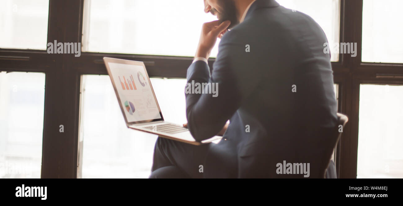 Manager with a laptop, working with financial charts near a large ...
