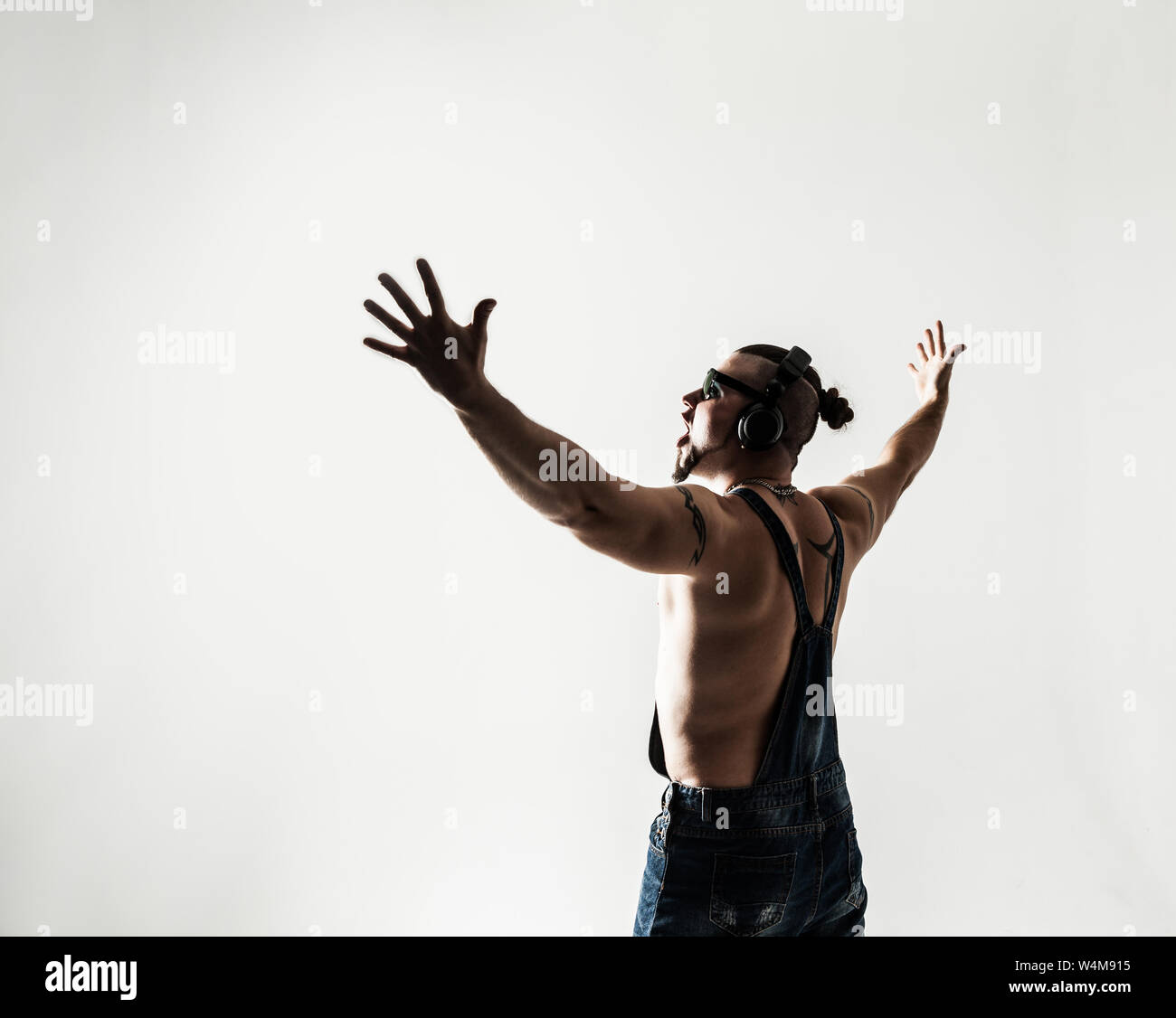 side view - DJ - rapper with headphones on a light background performs ...