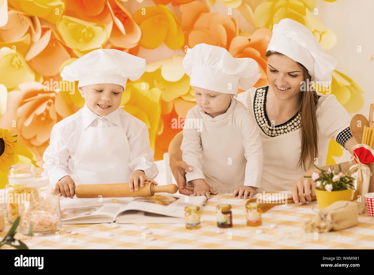 Happy mother with her children, cooking dinner in the kitchen on a ...