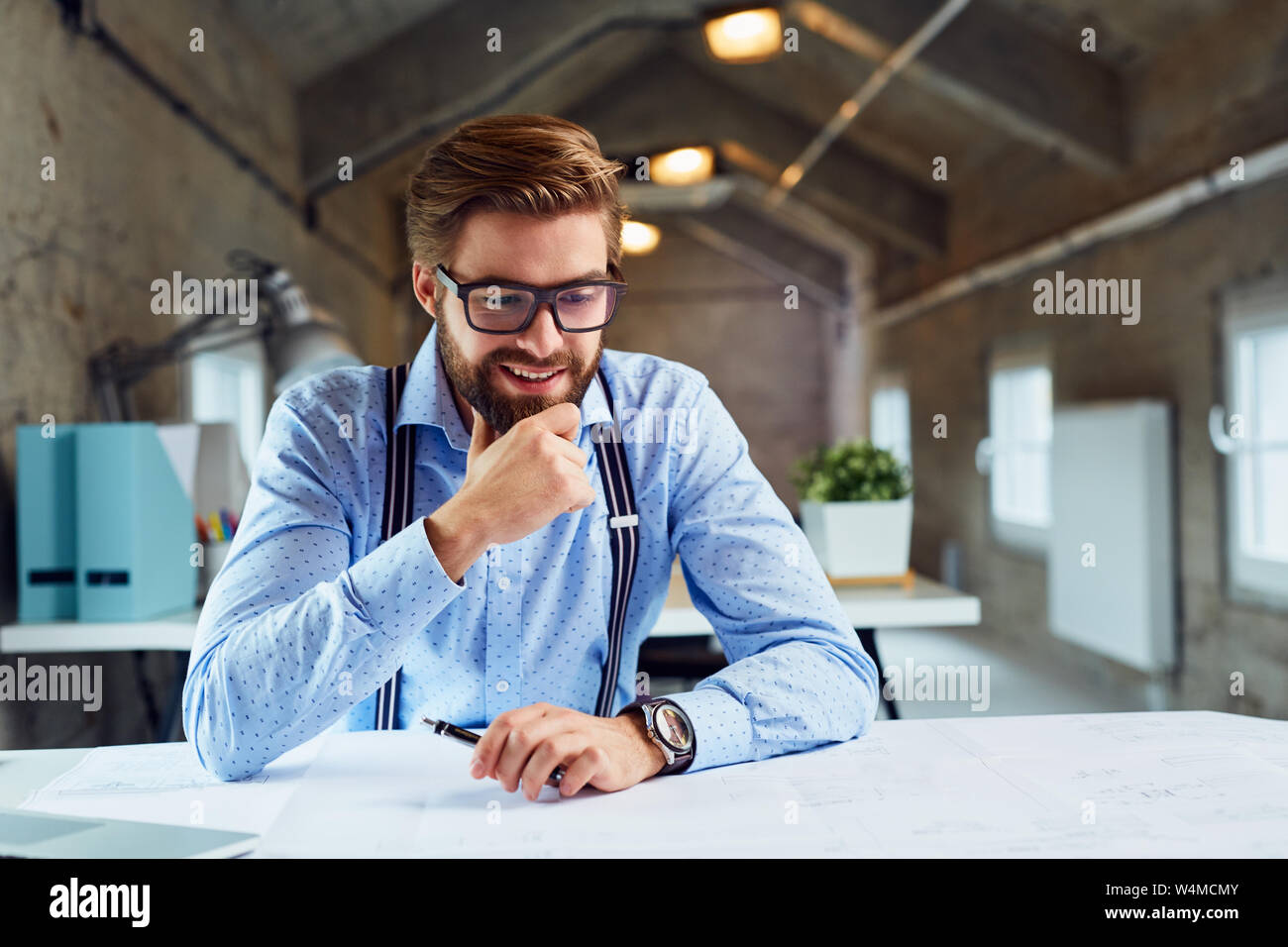 Handsome architect looking on blueprints at modern office Stock Photo ...