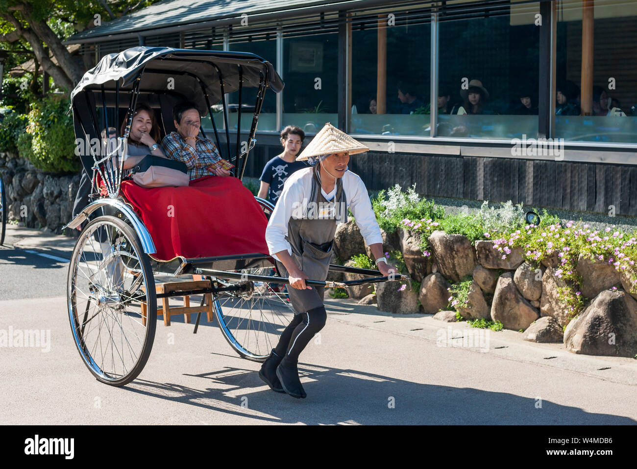 Pulled rickshaw travelling along street in Arashiyama, Japan with two ...