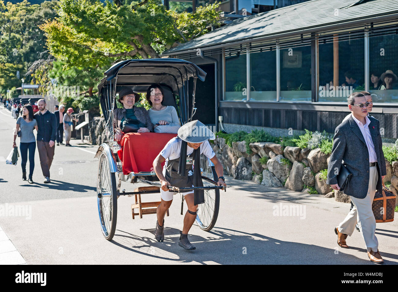 Pulled rickshaw travelling along street in Arashiyama, Japan with two ...