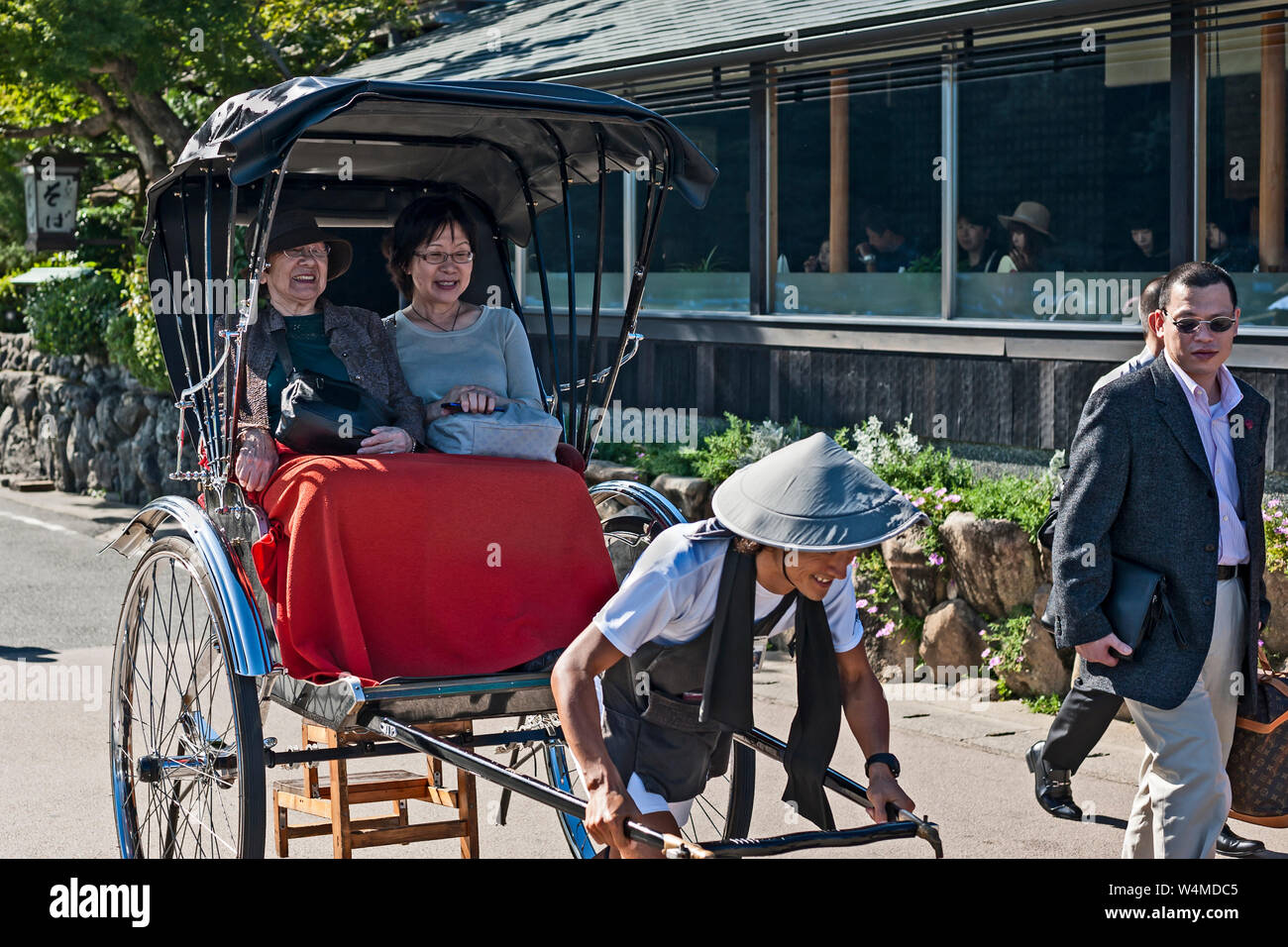 Pulled rickshaw travelling along street in Arashiyama, Japan with two ...