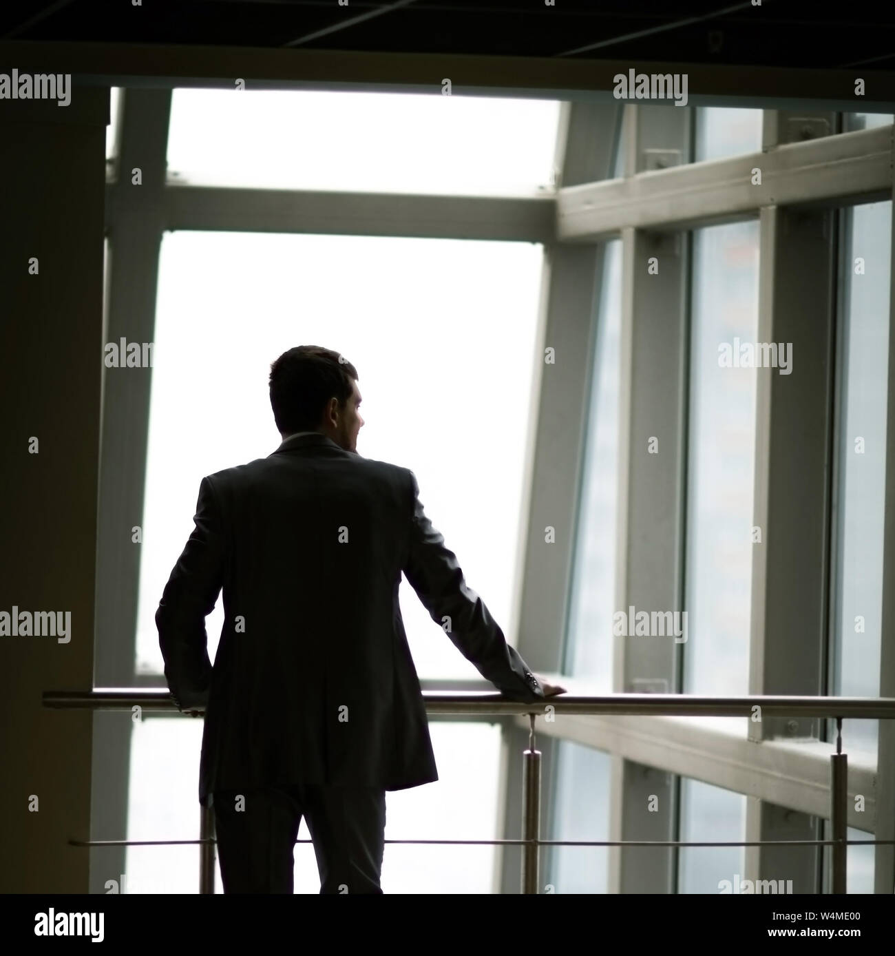 successful businessman by the window in the lobby of a modern office ...