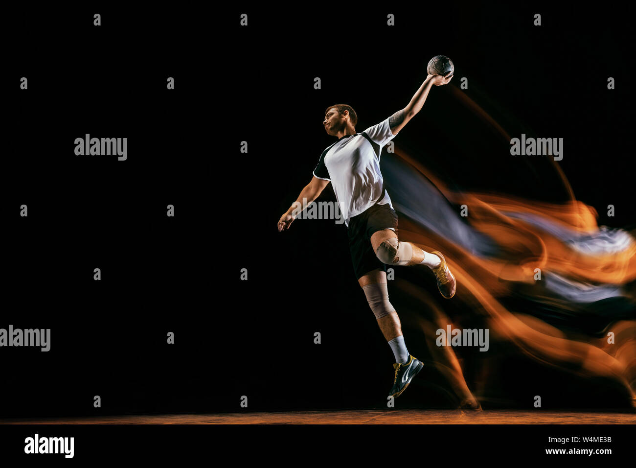 Caucasian young handball player in action and motion in mixed lights ...