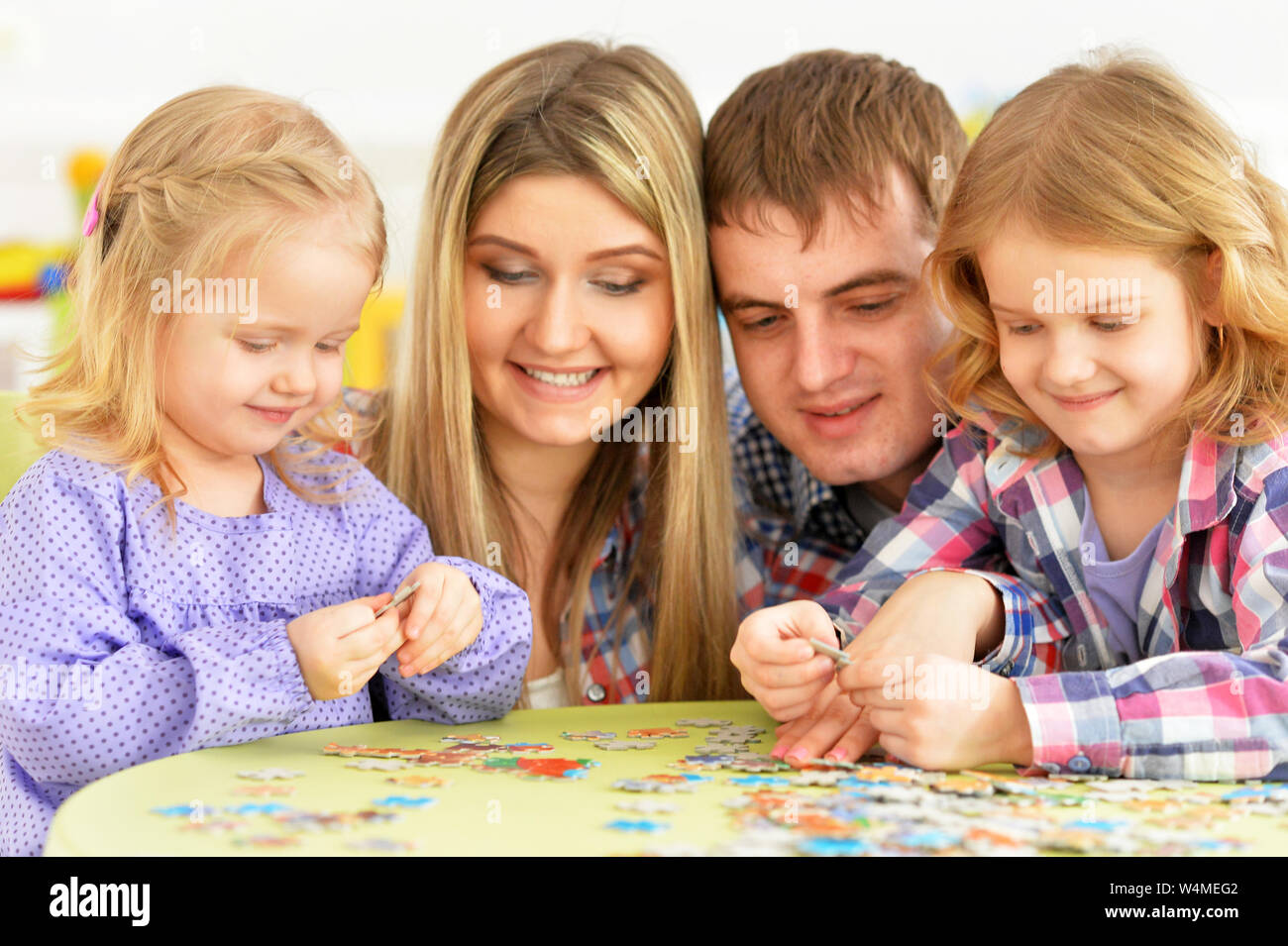 Parents and children collecting puzzle and posing at home Stock Photo ...
