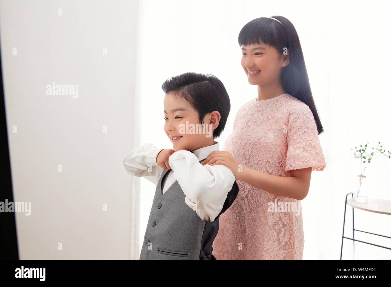 Sister help my brother finish clothes Stock Photo - Alamy