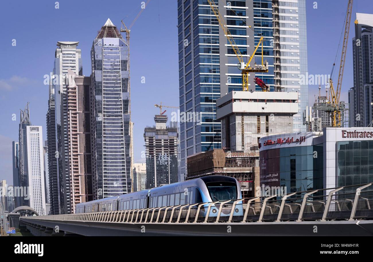 In Dubai, a metro train travels on a viaduct between skyscrapers. The ...