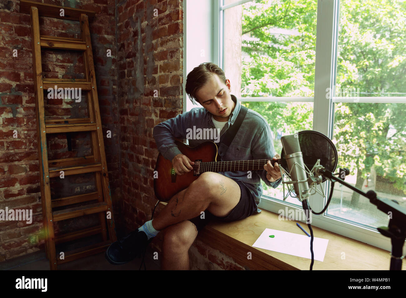 Young man recording music video blog, home lesson or song, playing ...