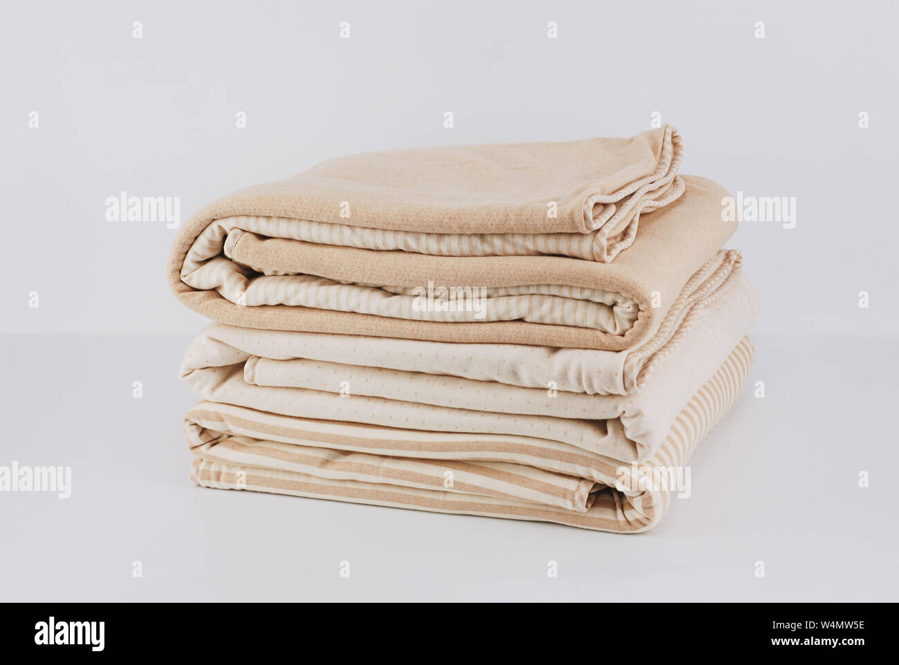 Closeup pile folded natural beige cotton blanket for kid on white ...