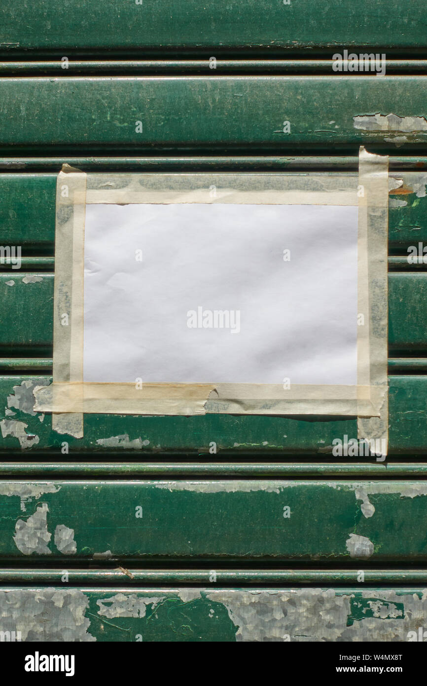Blank paper with scotch tape on the door closed by roller shutter ...