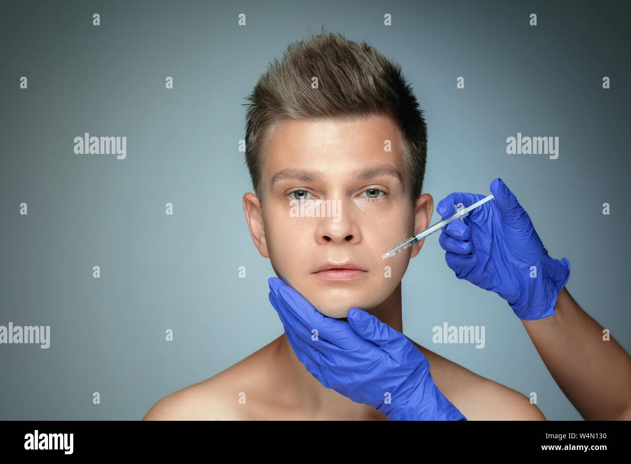 Close-up portrait of young man isolated on grey studio background ...