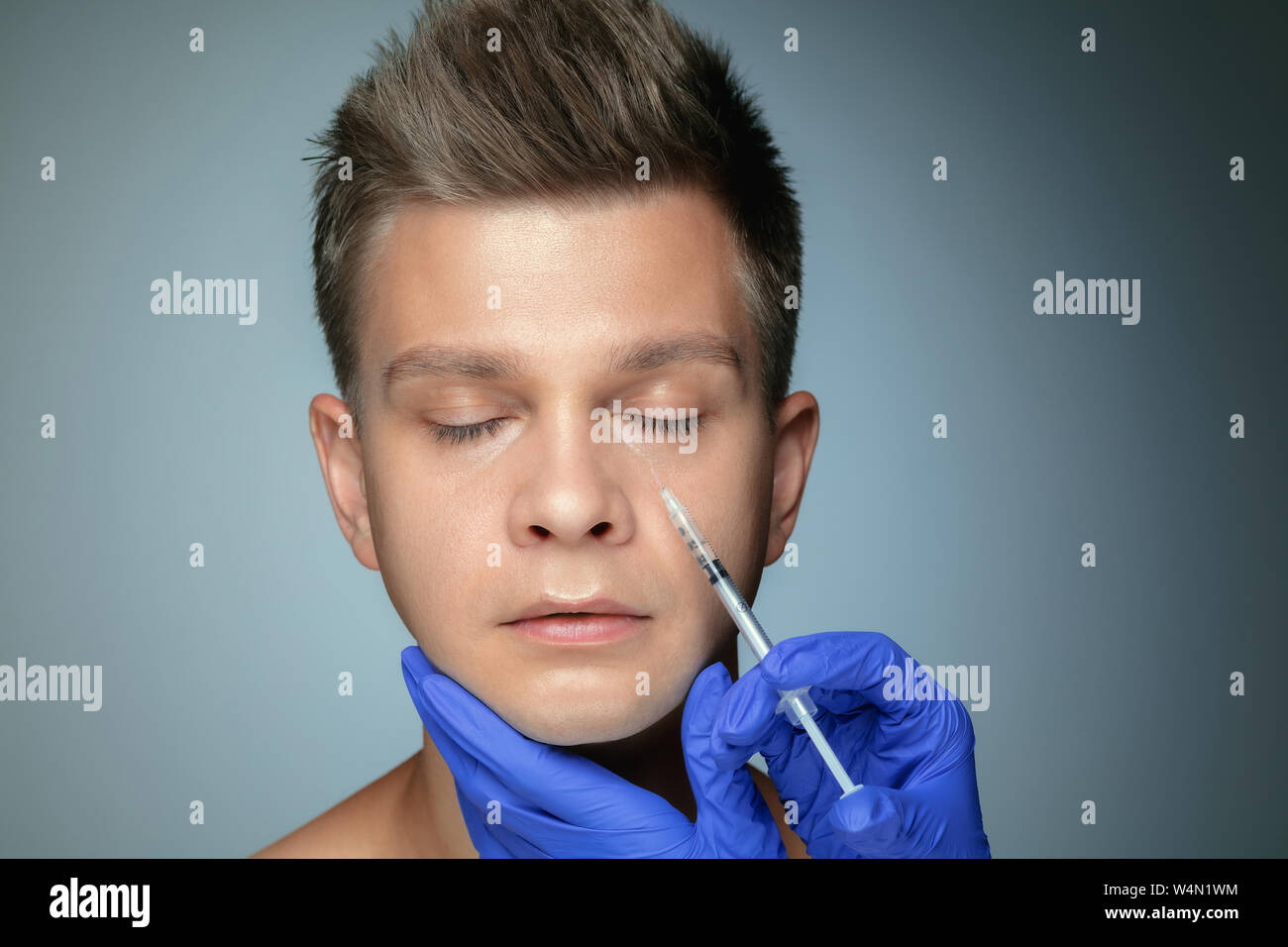 Close-up portrait of young man isolated on grey studio background ...