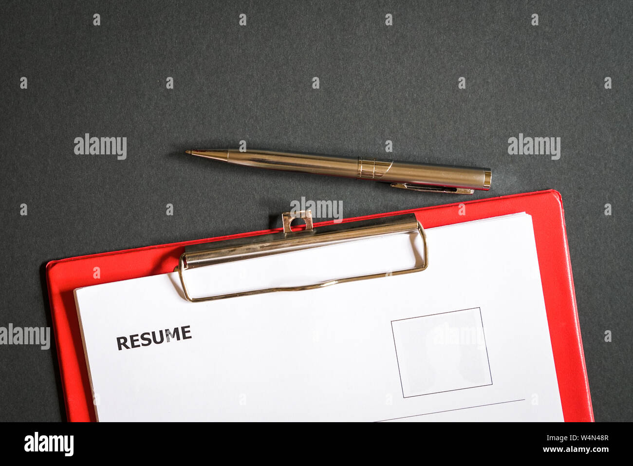 Review resume of applicants on clipboard with a pen. Top view of office ...