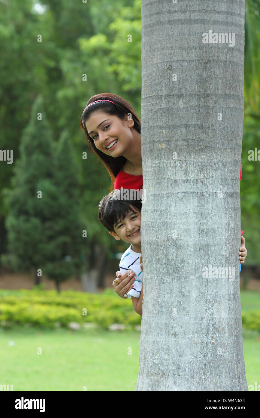 Boy peeking around tree trunk hi-res stock photography and images - Alamy
