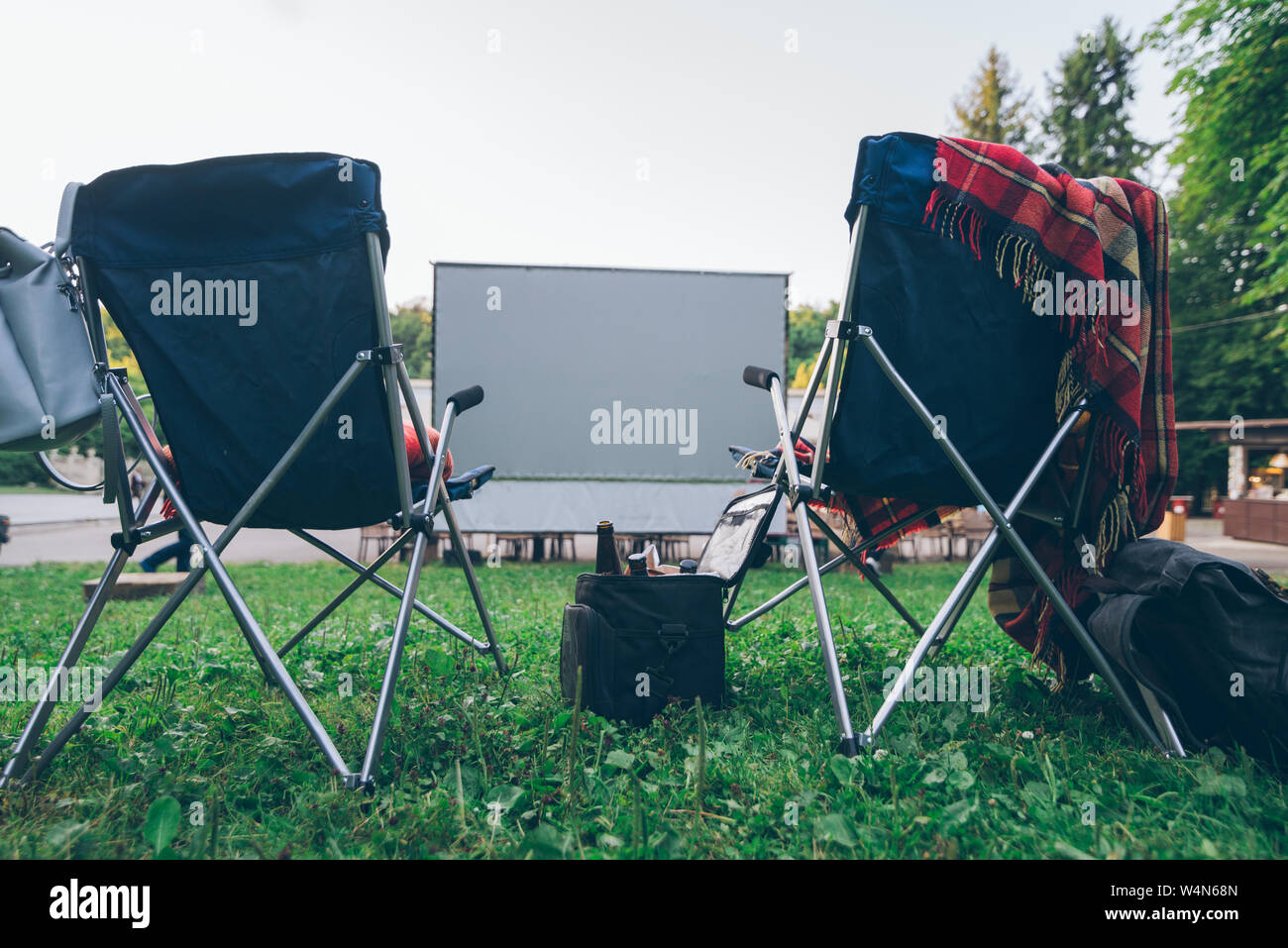 open air cinema concept folding chairs in front of big white movie ...