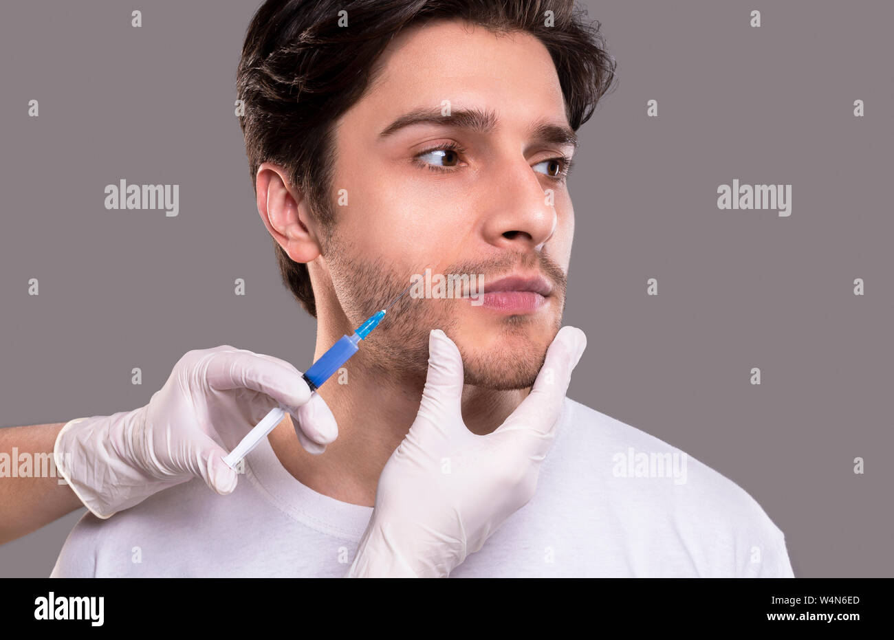 Young man getting beauty injection, grey studio background Stock Photo ...